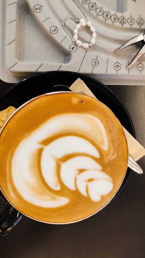 A Cup of Coffee with a Foam Pattern is on the Table in the Cafe. View ...