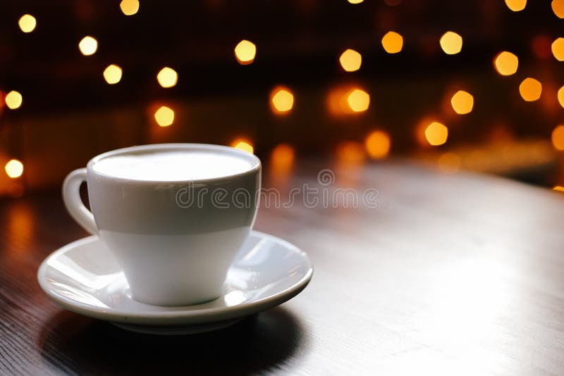 A Cup of Coffee on Wooden Table. Lights on the Background. Front View ...