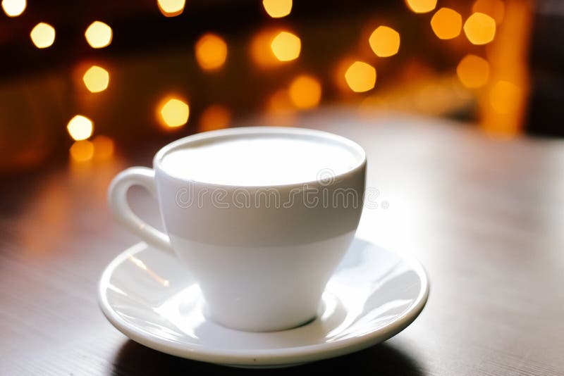A Cup of Coffee on Wooden Table. Lights on the Background. Front View ...