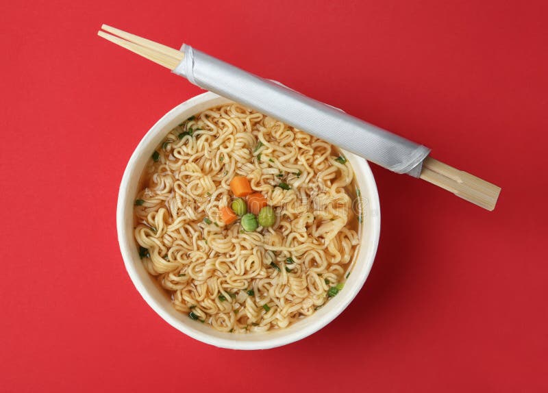 Cup of Cooked Instant Noodles with Chopsticks on Color Background Stock ...