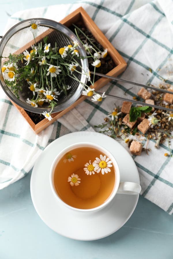 Cup of Delicious Camomile Tea and Sieve on Light Table Stock Photo ...