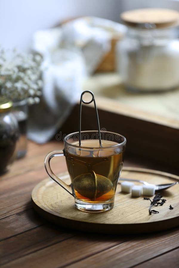 Cup of Freshly Brewed Tea with Snap Infuser and Sugar Cubes on Wooden ...