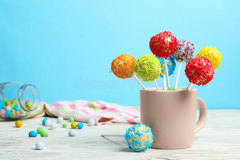 Cup with Tasty Cake Pops on Table Against Light Blue Background Stock ...
