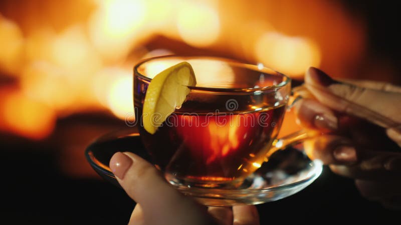 Cup with Tea in Female Hands by the Fireplace Where the Fire Burns ...