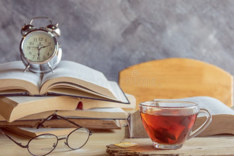 A Cup of Tea with Glasses and Alarm Clock on Stack Books Stock Image ...
