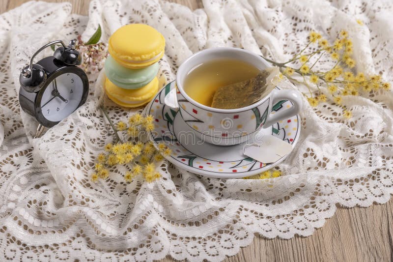 A Cup of Tea Next To an Alarm Clock that Strikes Five O Clock on a Lace ...