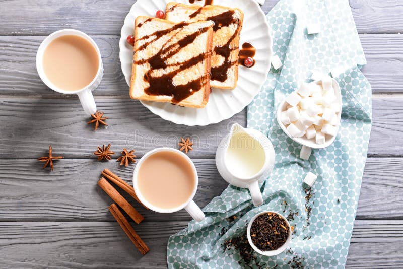 Cups of Aromatic Tea with Milk and Delicious Toasts on Table Stock ...