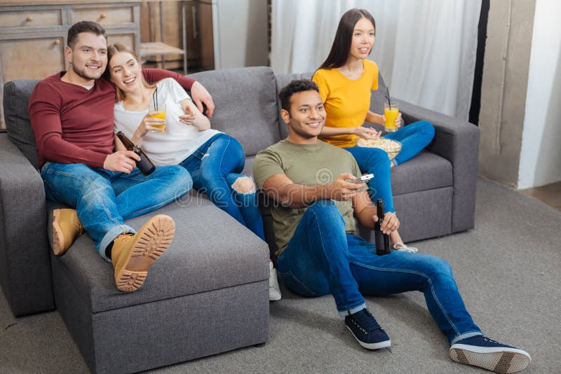 Curious Friends Smiling while Watching an Interesting Program on TV ...