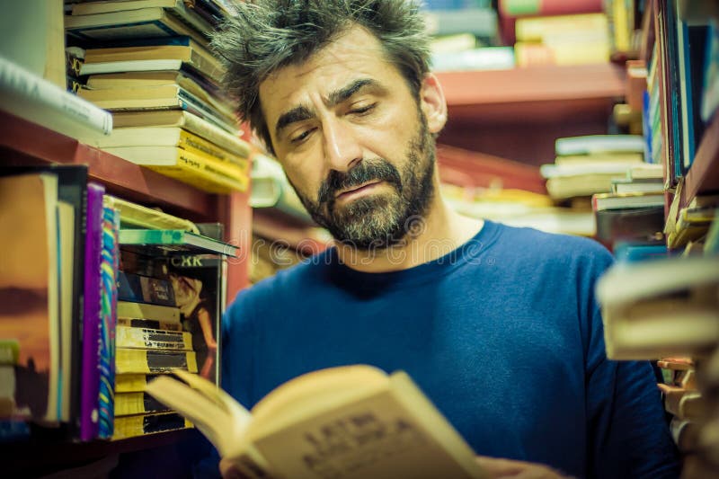Curious Man Reading Book between the Shelves in the Library Stock Image ...