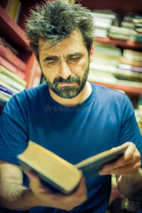 Curious Man Reading Book between the Shelves in the Library Stock Image ...