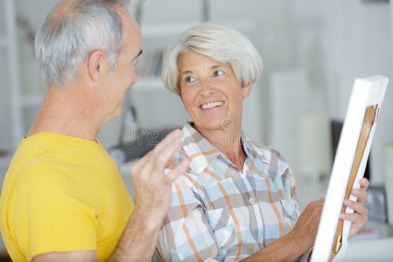Curious Senior Couple Looking at Frame Together Stock Image - Image of ...