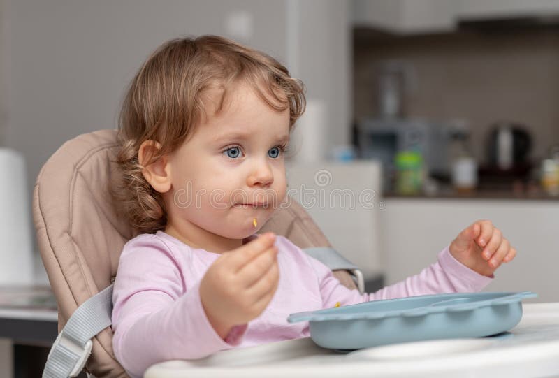 A Curious Toddler Concentrating on Self-feeding during a Calm Mealtime ...