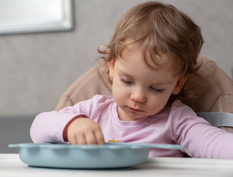 A Curious Toddler Exploring Her Meal while Sitting at the Table in a ...
