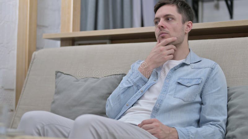 Curious Young Man Thinking while Sitting on Sofa Stock Photo - Image of ...