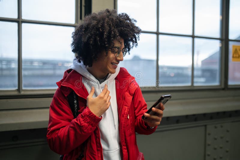 Curly-haired Young Guy in Red Jacket with a Phone in Hands Stock Photo ...