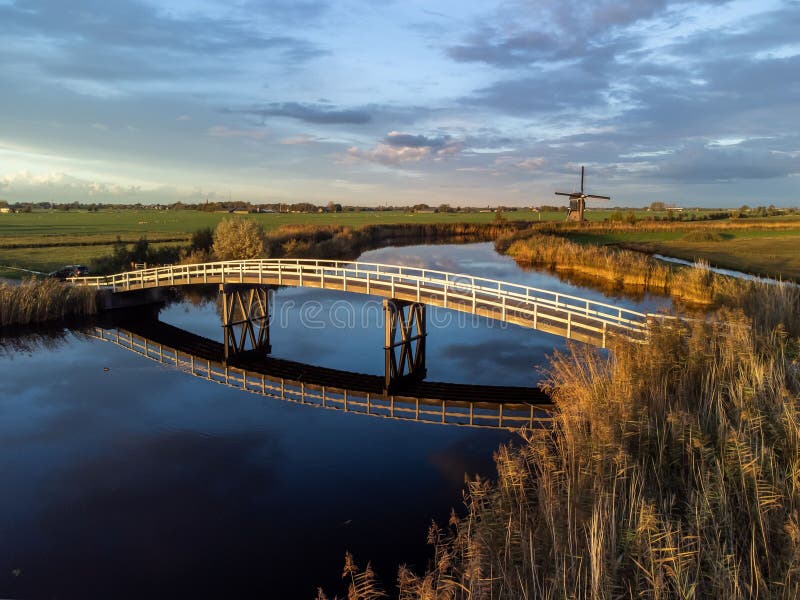 Curved Bridge Over a River with Its Image Reflecting in the Water, in a ...