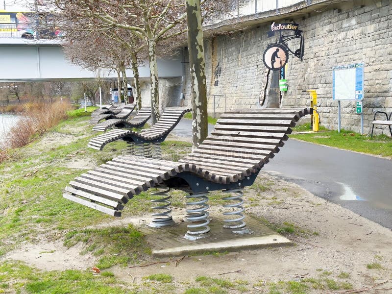 Curved Wooden Benches on Springs by River Path in Urban Park Setting ...