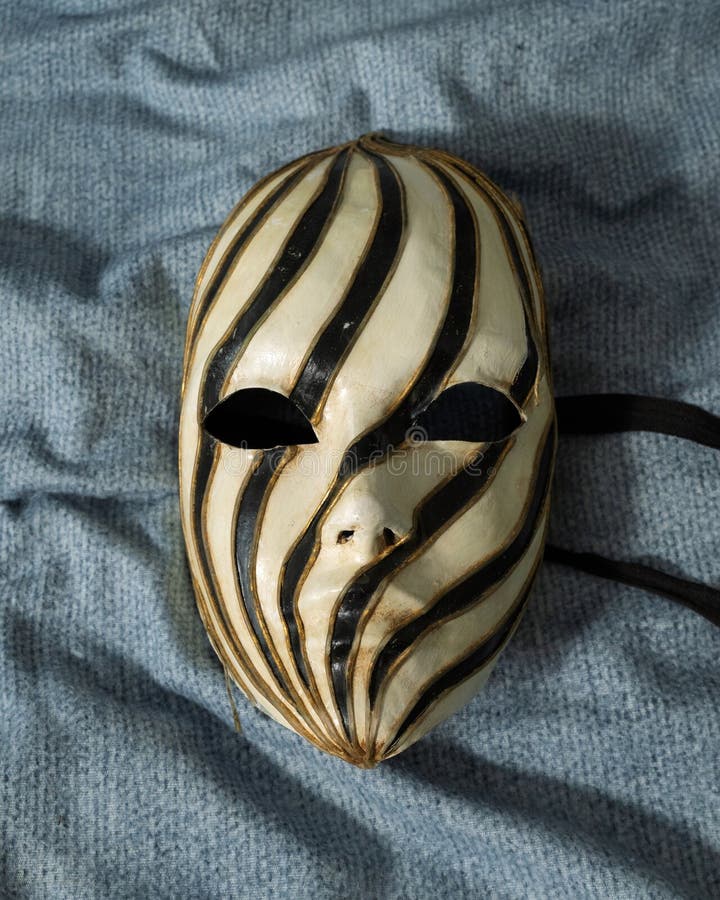A Curvy Zebra Mask Laying Down on a Light Blue Bed Sheet Stock Photo ...