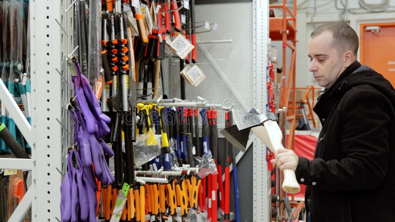 Customer Carefully Examining Axe Handle among Gardening Tools ...