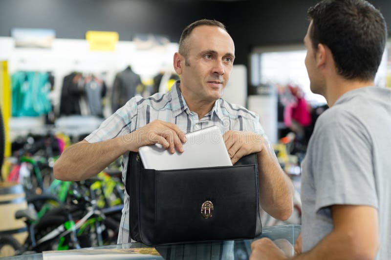 Customer and Shop Manager Going through Paperwork in Bike Sho Stock ...