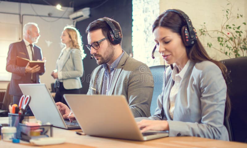 Customer Support Operators Working on Laptops in Office. Focus on ...