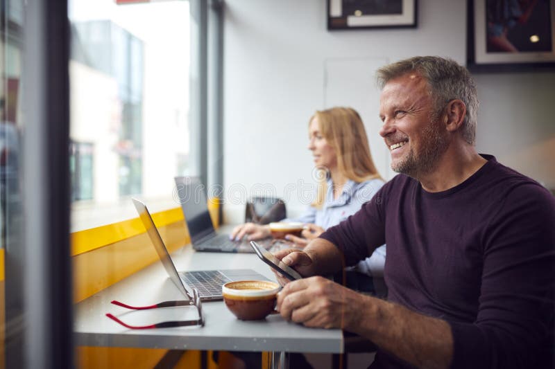 Customers in Coffee Shop Window Working on Laptops Using Mobile Phones ...