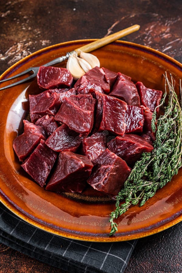 Cut Beef or Veal Raw Heart in a Rustic Plate with Herbs. Dark ...