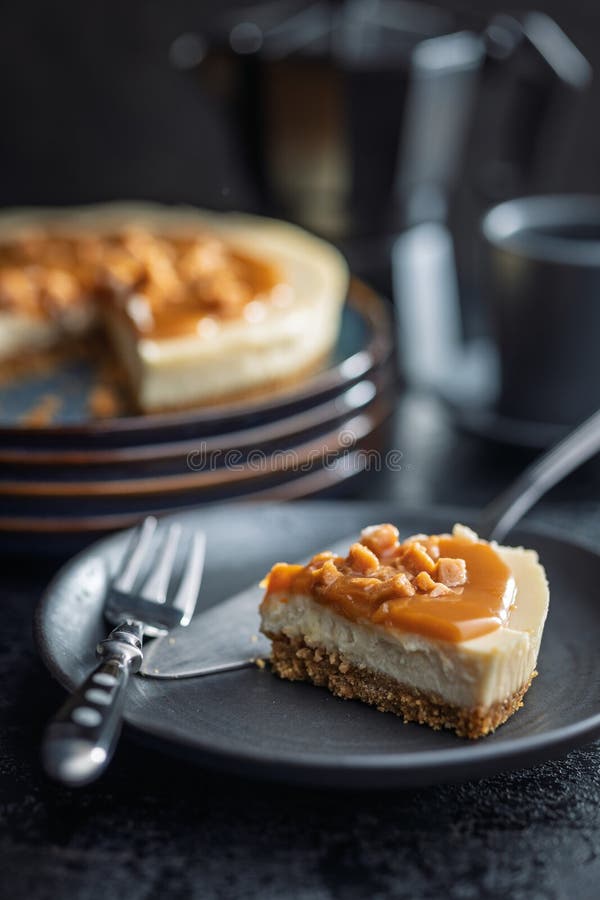 A Cut Piece of Cheesecake with Caramel Topping on Plate on Black Table ...