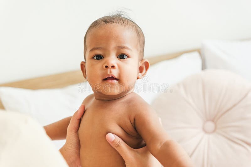 A Cute Baby is Being Held, Looking Directly at the Camera with a ...