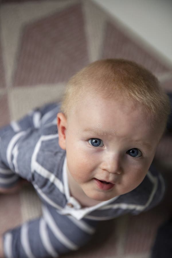 A Cute Baby Boy Sat on a Nursery Floor Looking Up To the Camera Stock ...