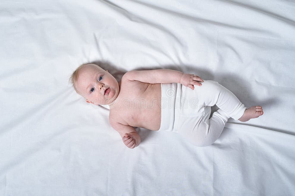 Cute Blond Baby with a Torso Lying on White Sheets. Top View Stock ...