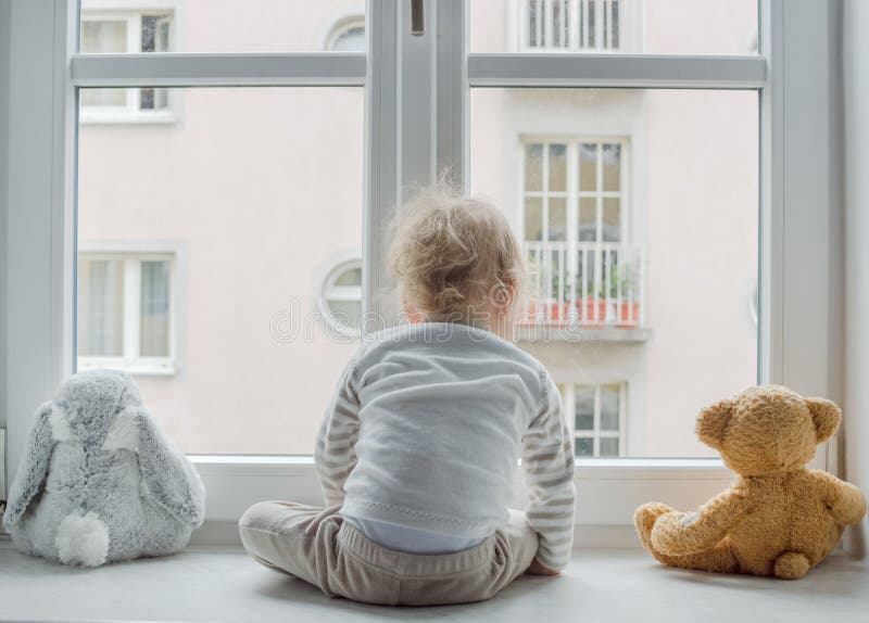 Cute Boy at Home Looking through the Window and Playing with His Toys ...