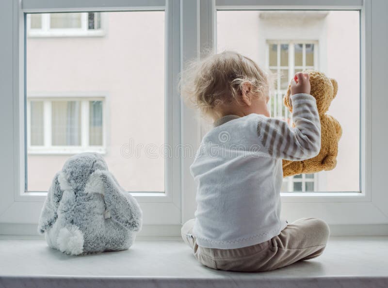 Cute Boy at Home Looking through the Window and Playing with His Toys ...