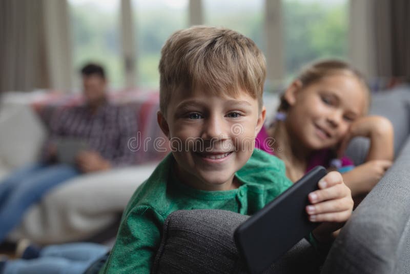Cute Boy with Mobile Phone Looking at Camera on Sofa in a Comfortable ...