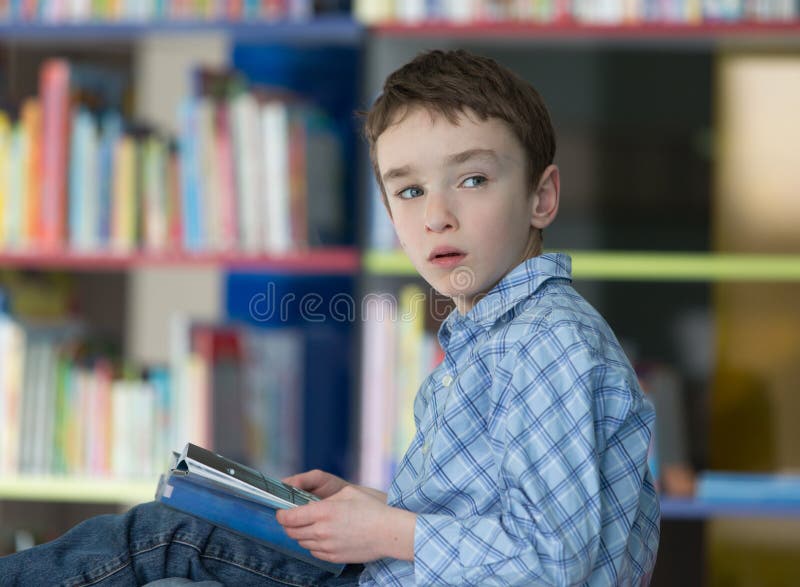 Cute Boy Reading Book in Library Stock Photo - Image of child, desk ...