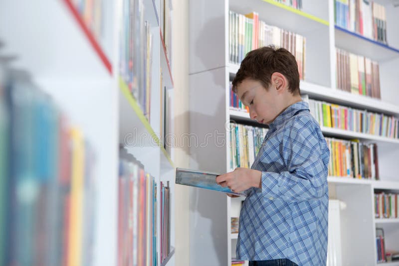 Cute Boy Reading Book in Library Stock Photo - Image of reading ...