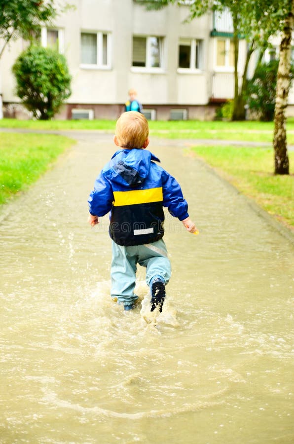 Happy Children in Water-proof Clothes Running through the Puddle after ...