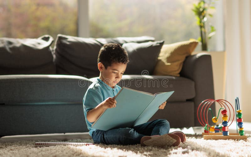 Cute Boy Sitting on a Carpet at Home and Reading Stock Photo - Image of ...