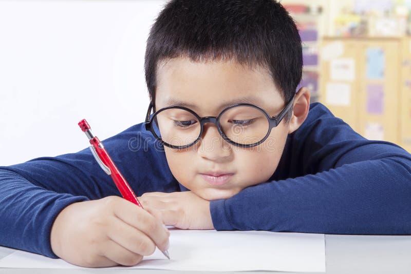 Cute Boy Writing on the Paper in Class Stock Photo - Image of ...