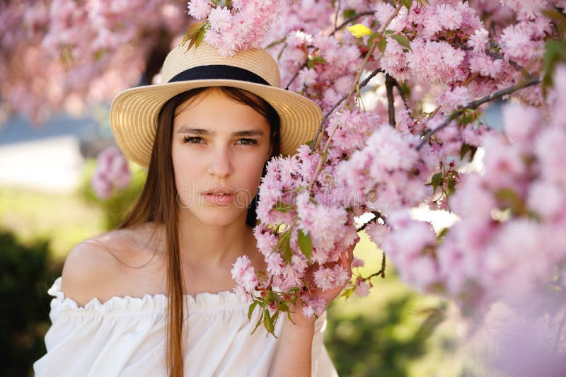 Cute Caucasian Girl Standing Near Sakura Tree Looking Straight At The