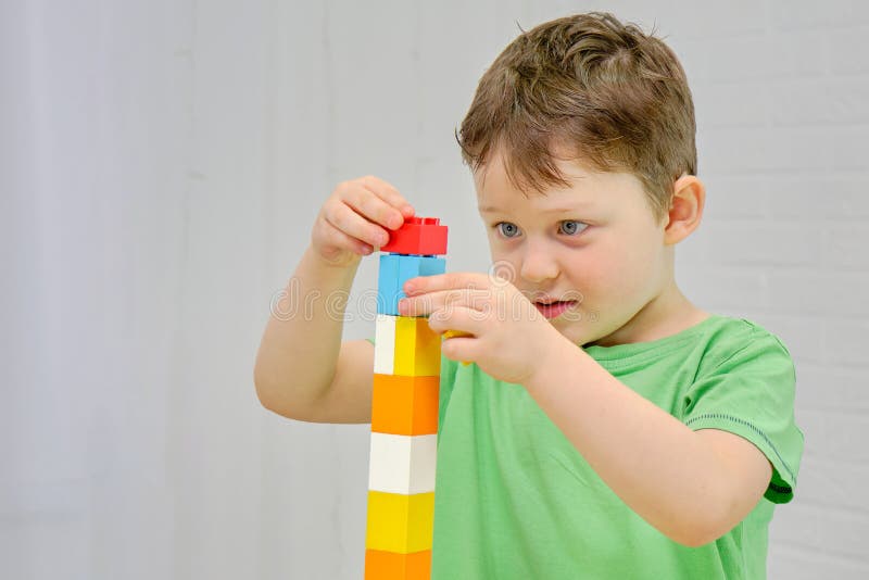 A Cute Child Builds a High Pyramid from Constructor S Cubes. the Boy is ...