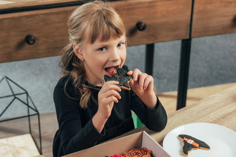 Cute Child Eating Halloween Cookie and Looking at Camera Stock Image ...