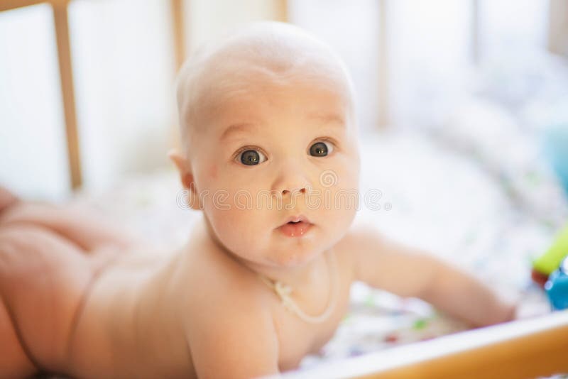 A Cute Child is Interested in Looking through the Frame of the Crib ...