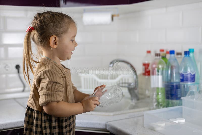 Cute Child Sorting Plastic in the Kitchen. the Daughter Follows the ...