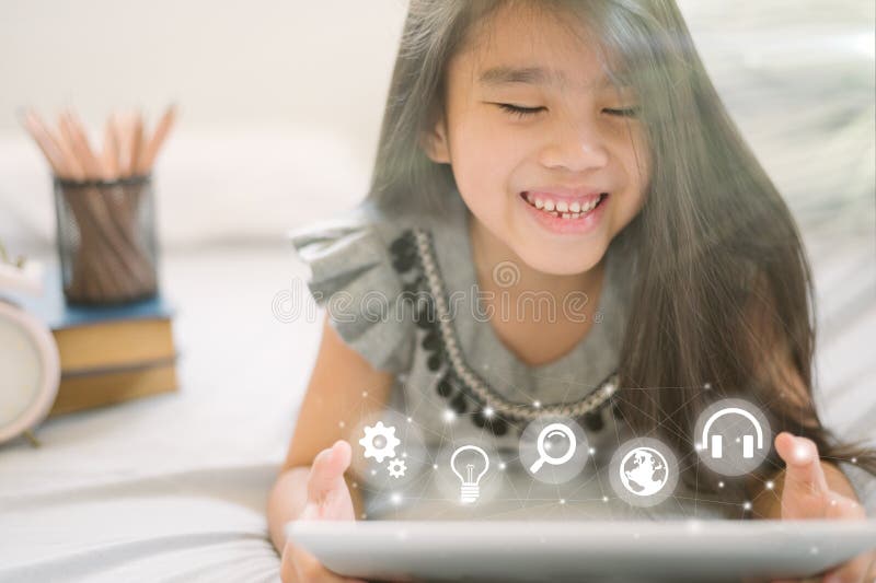 Cute Child Using a Tablet and Smiling while Sitting on Sofa at Home ...