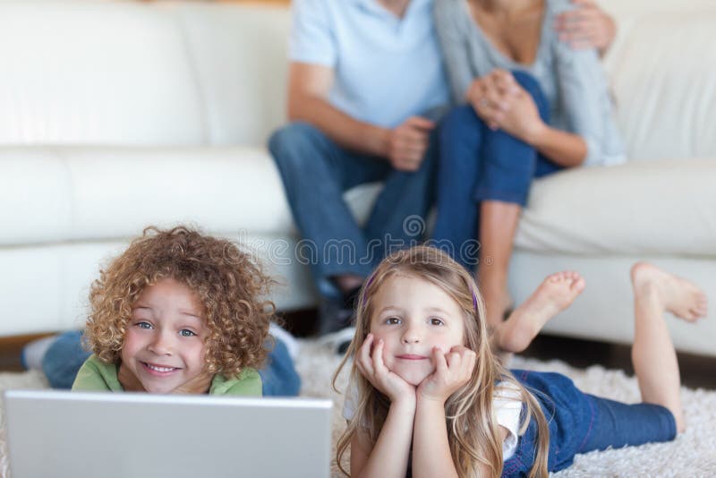 Cute Children Using a Laptop while Their Parents are Watching Stock ...