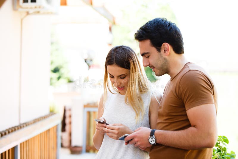 Cute Young Couple Standing and Using Phone Stock Photo - Image of date ...