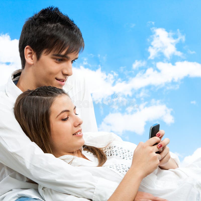 Cute Couple Socializing with Smart Phone Outdoors. Stock Image - Image ...