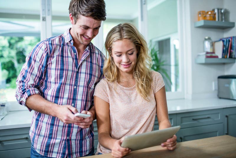 Cute Couple Using Tablet Computer in the Kitchen Stock Image - Image of ...