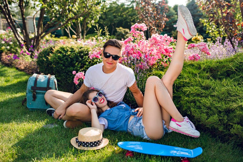 Cute Couple Young People In Sunglasses Is Chilling On Grass In Summer